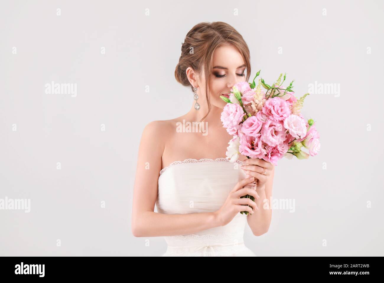 Portrait of beautiful young bride with wedding bouquet on light ...