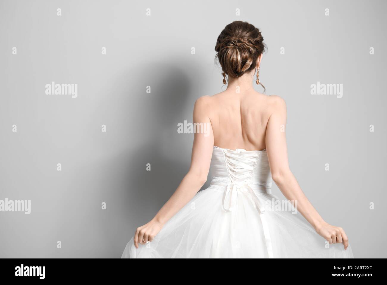 Beautiful young bride on grey background, back view Stock Photo - Alamy