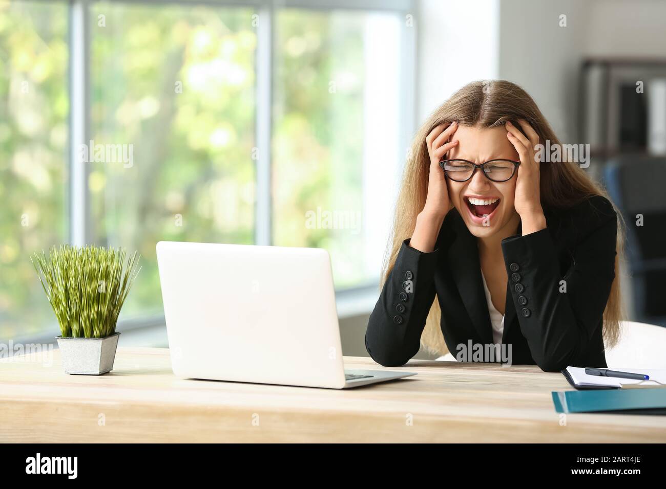 Stressed young woman at workplace Stock Photo - Alamy