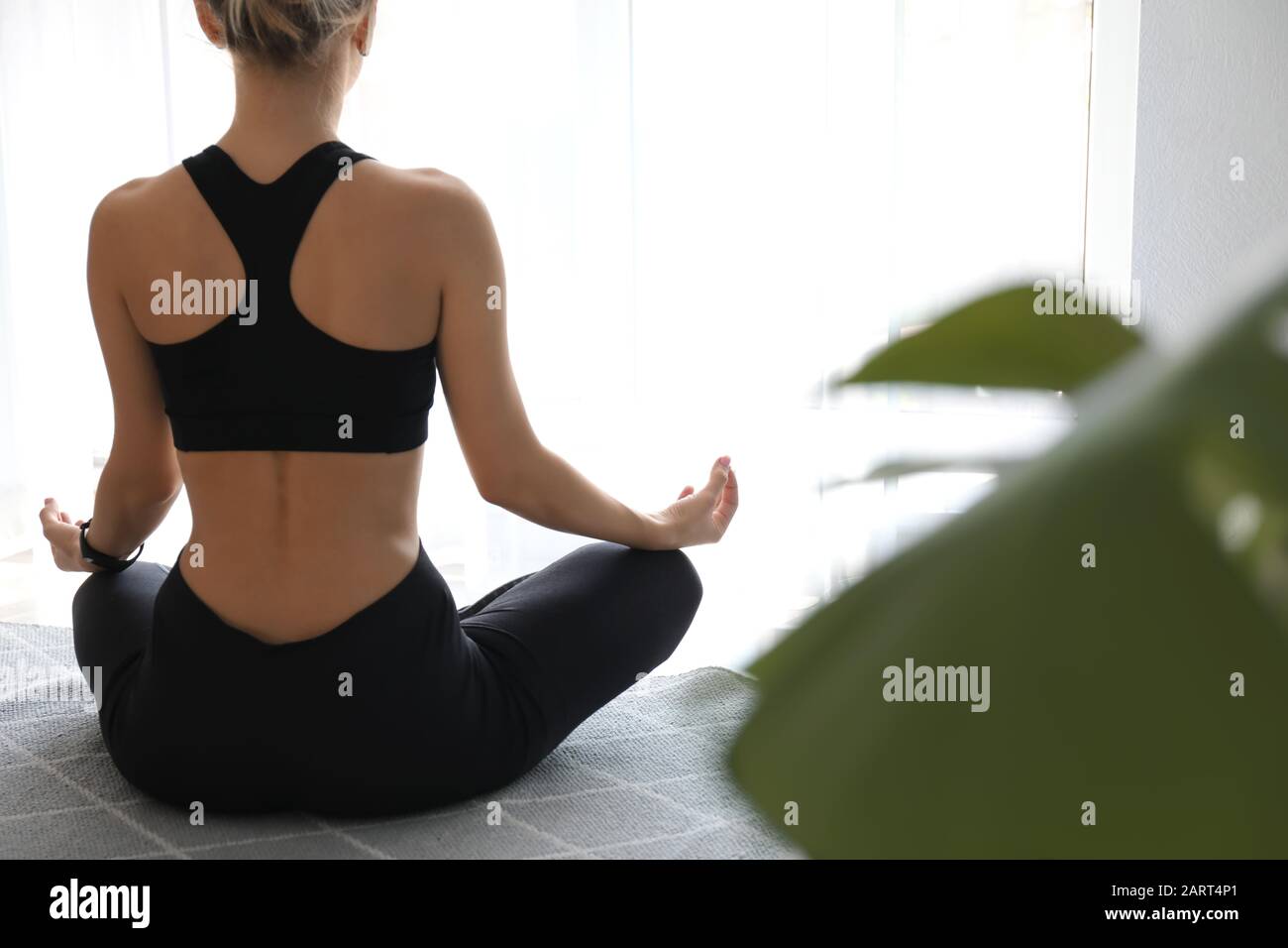 Young woman meditating at home, back view Stock Photo - Alamy
