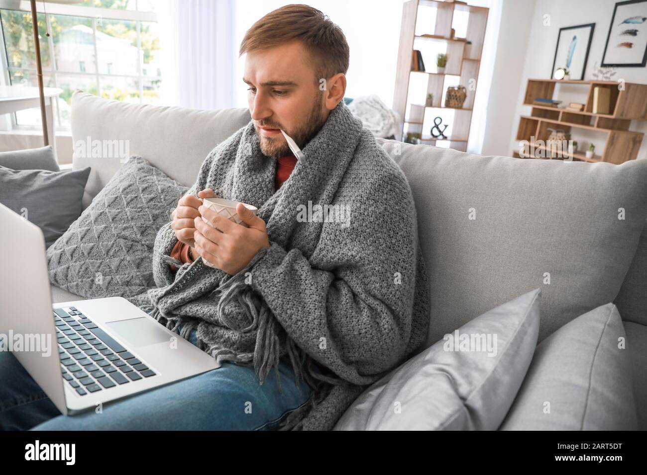 Sick man working on laptop at home Stock Photo - Alamy