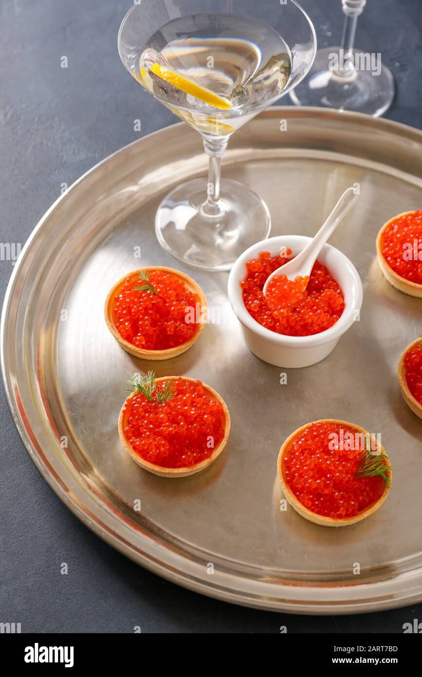Tray with red caviar and martini on grey background Stock Photo - Alamy