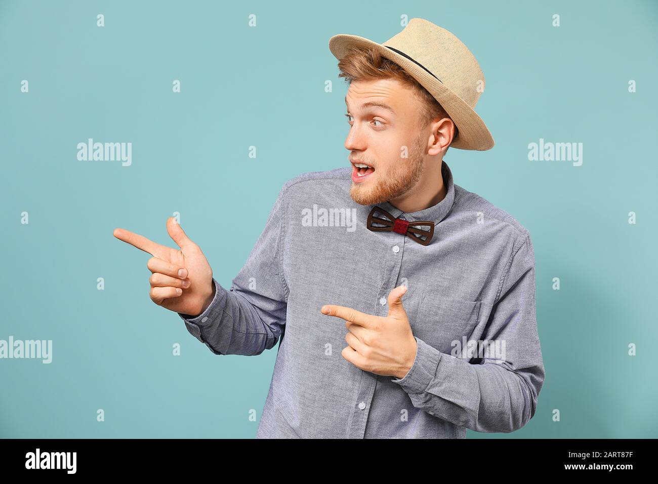 Portrait of surprised man pointing at something on color background ...
