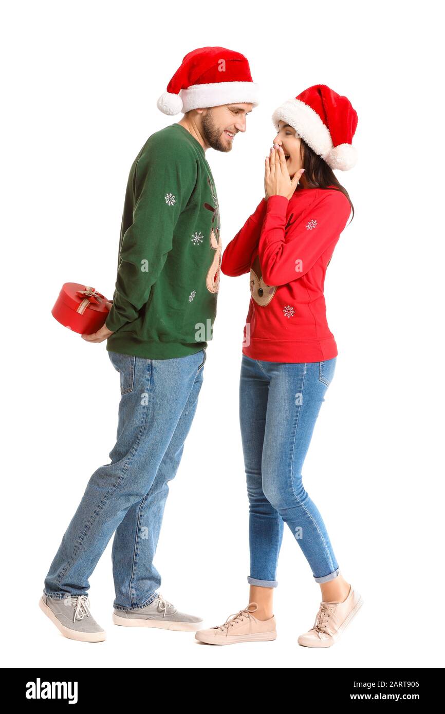 Man hiding Christmas gift for his wife behind back against white ...