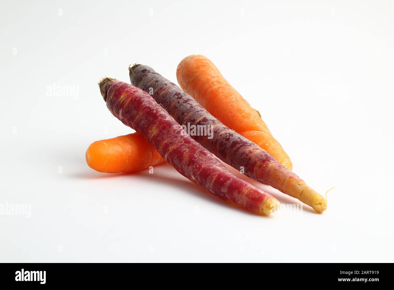 Black carrots and orange carrots over white background Stock Photo - Alamy