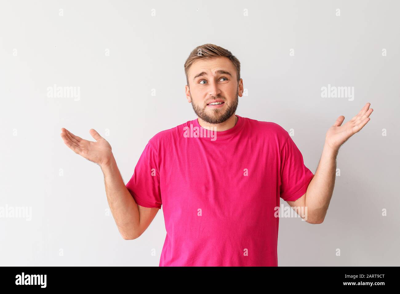 Confused young man on light background Stock Photo - Alamy