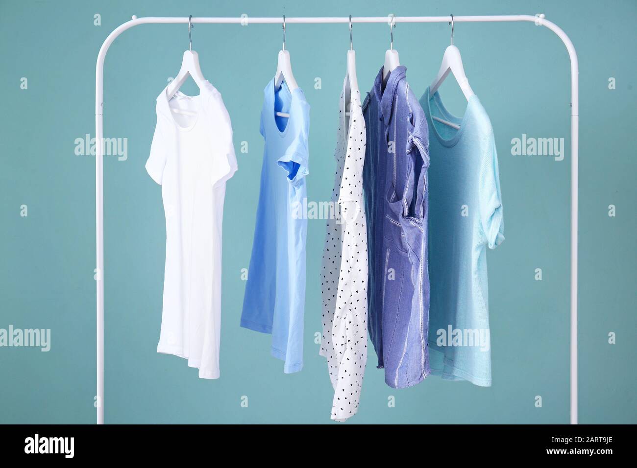 Rack with hanging clothes on color background Stock Photo - Alamy