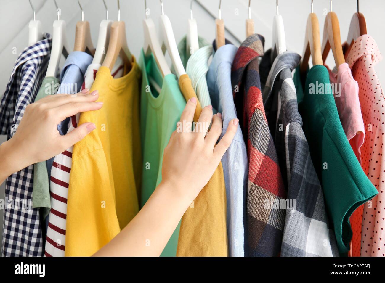 Woman choosing clothes hanging on rack Stock Photo - Alamy