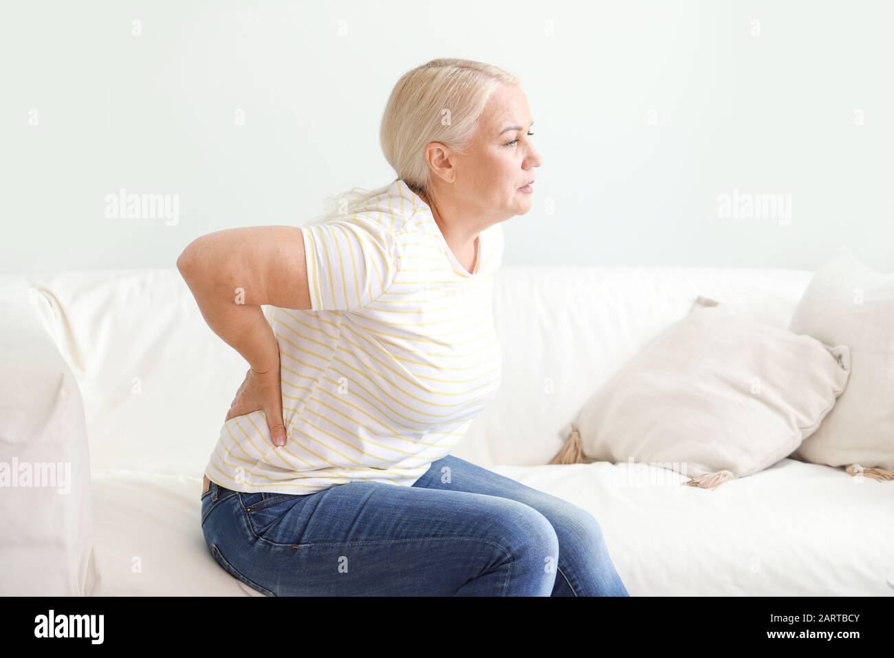 Mature woman suffering from back pain at home Stock Photo - Alamy