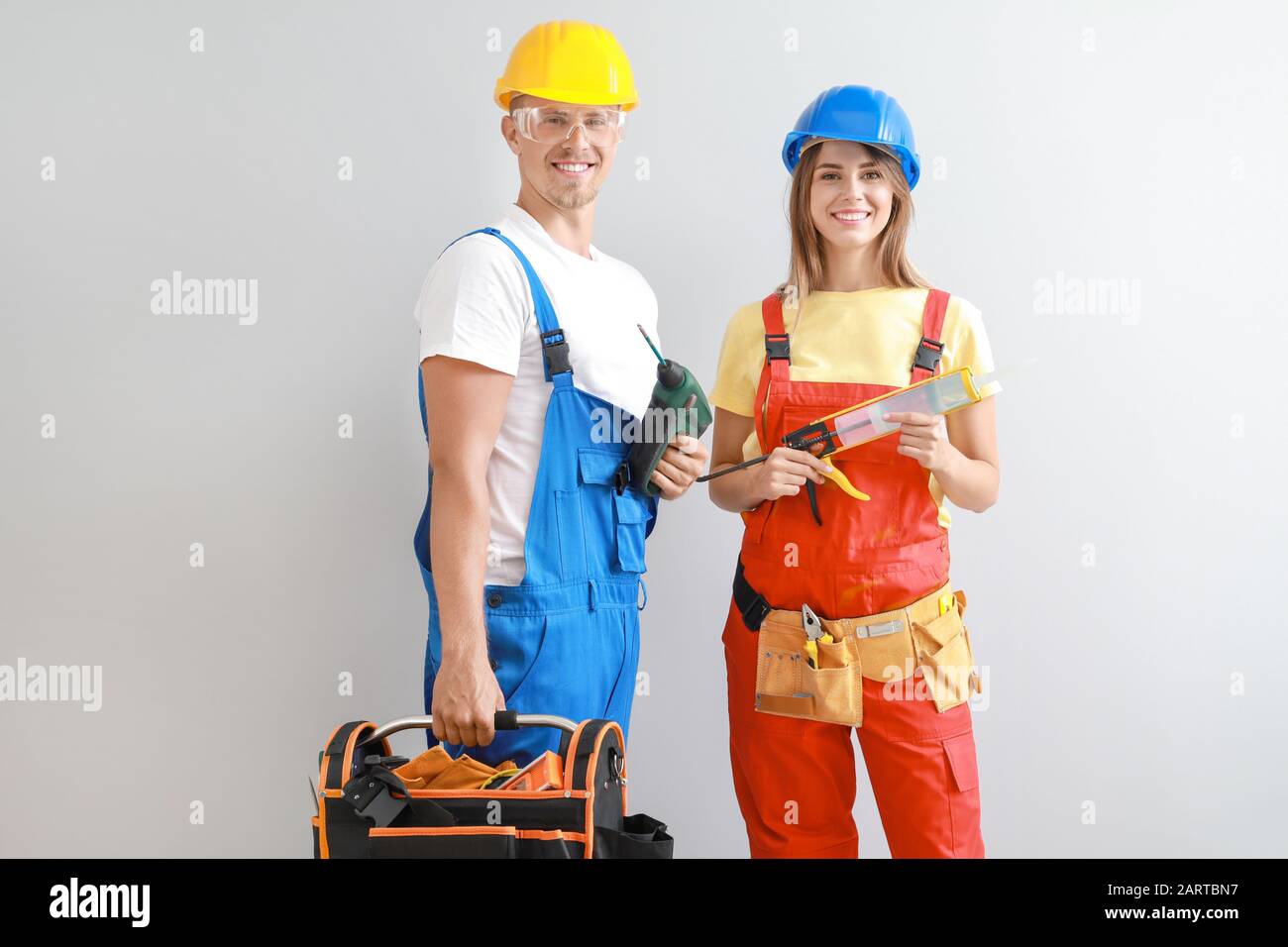 Happy young couple with tools on light background Stock Photo - Alamy