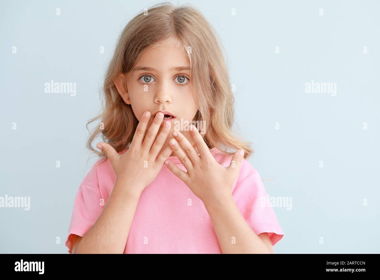 Surprised little girl on light background Stock Photo - Alamy