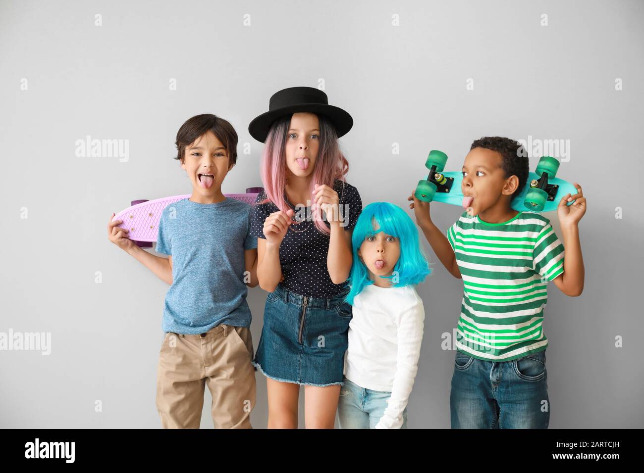 Grimacing little children with skateboards on light background Stock ...
