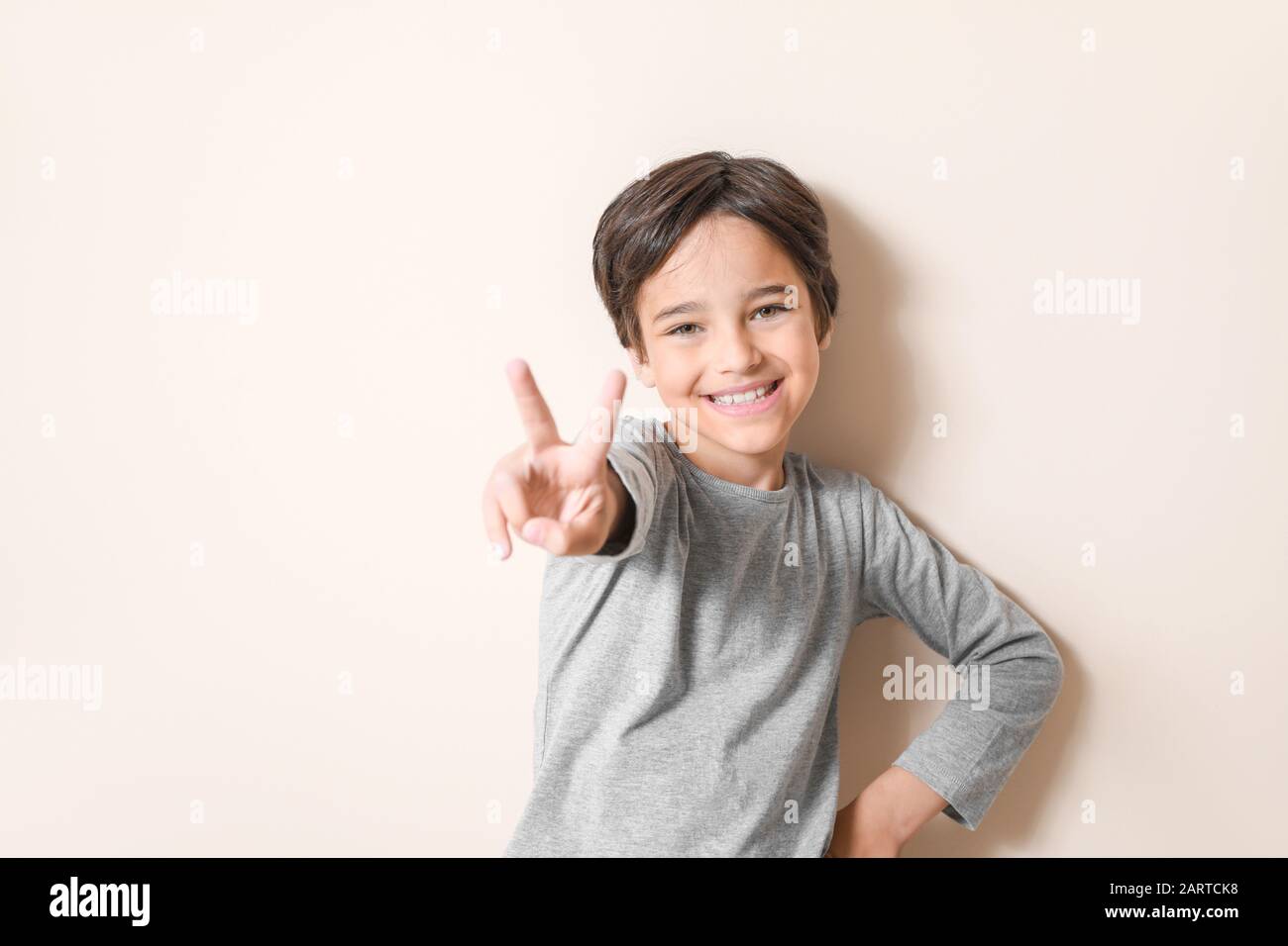 Happy little boy showing victory gesture on light background Stock ...