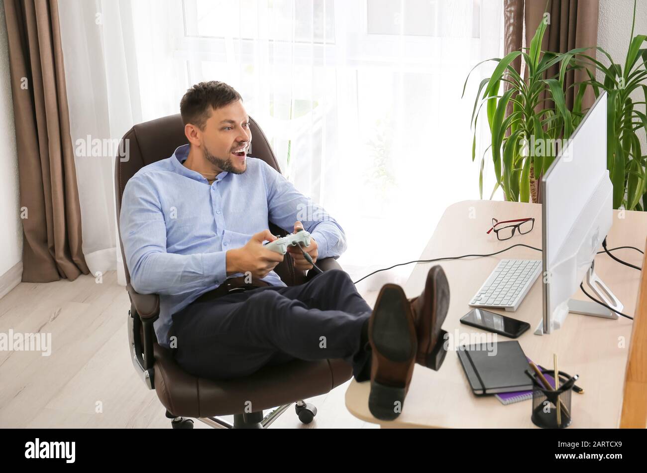 Carefree man playing video games in office Stock Photo - Alamy