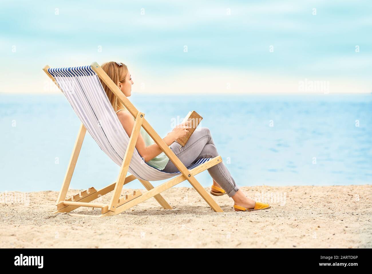 Woman reading book while relaxing on sea beach Stock Photo - Alamy