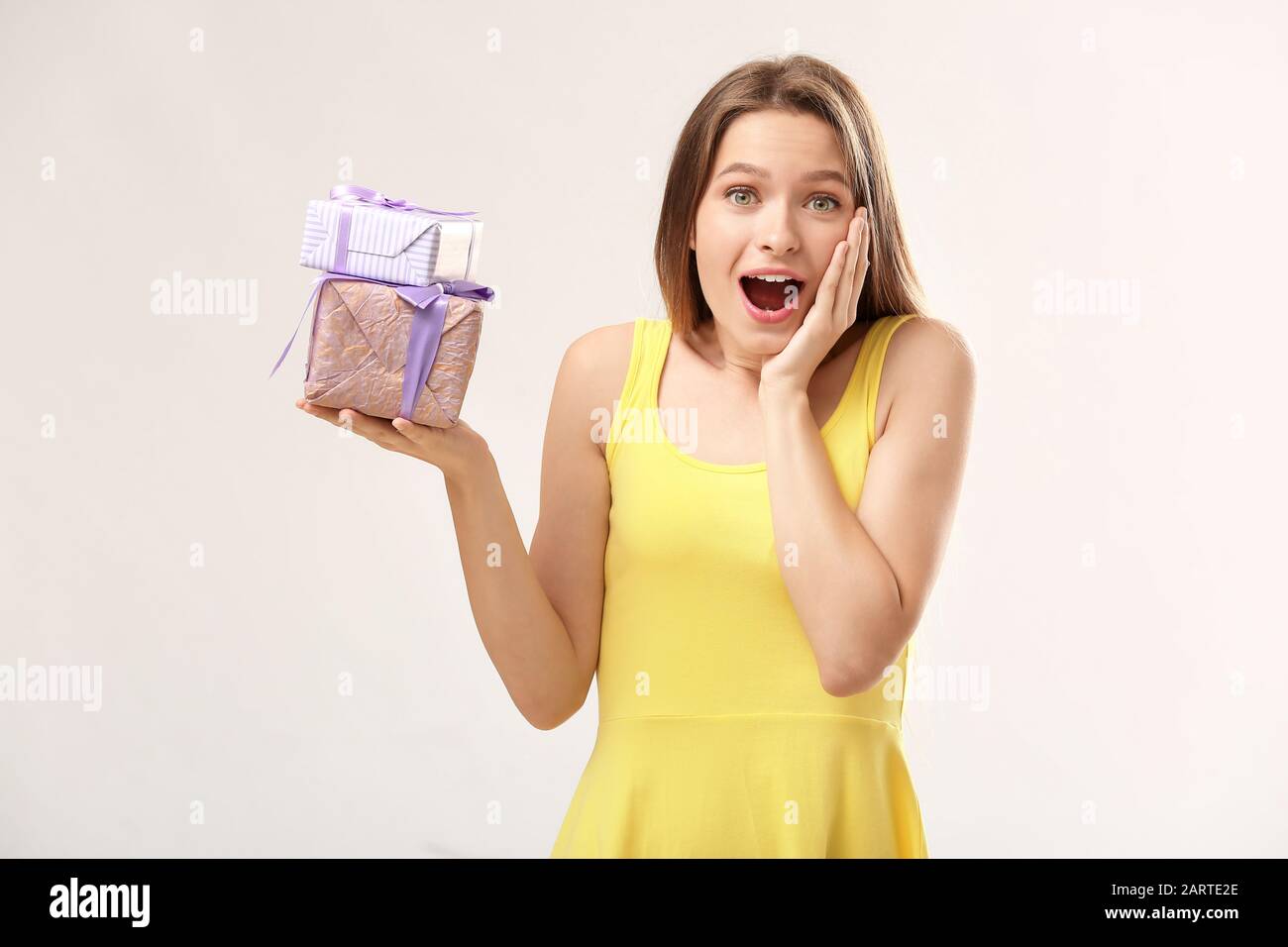 Surprised woman with gift boxes on white background Stock Photo - Alamy
