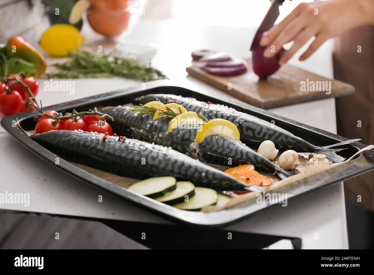 Tray with raw mackerel fish and vegetables on table in kitchen Stock ...