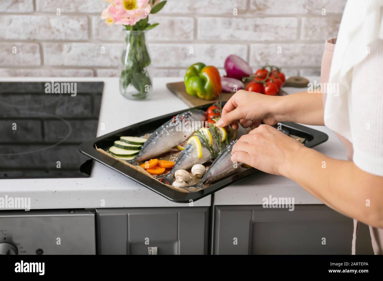 Woman cooking tasty mackerel fish in kitchen Stock Photo - Alamy