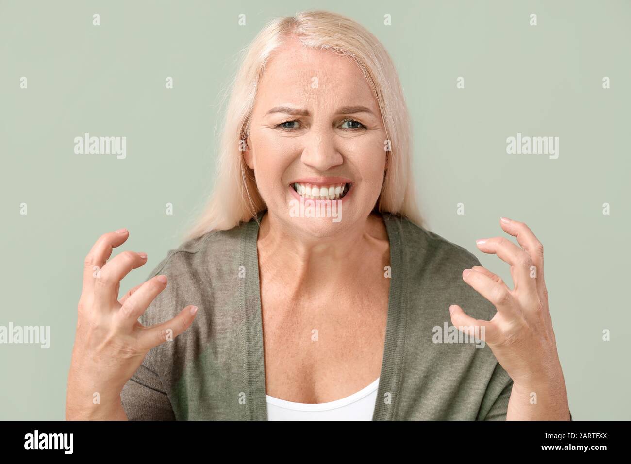 Angry mature woman on color background Stock Photo - Alamy