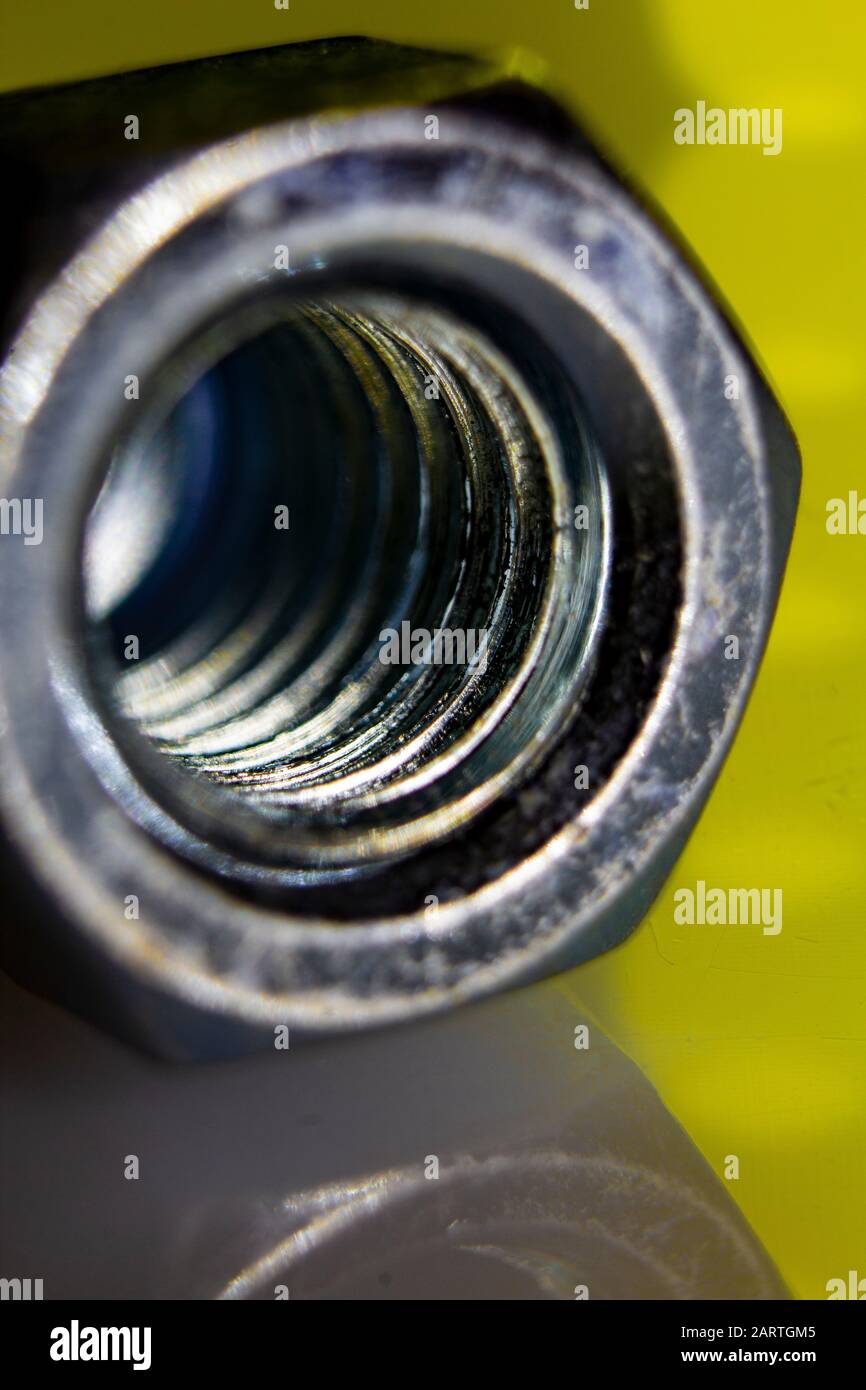 Thread of a hat nut in yellow background light Stock Photo - Alamy