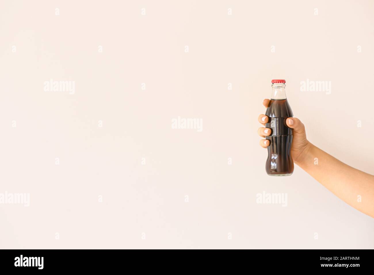 Female hand with bottle of cola on light background Stock Photo - Alamy