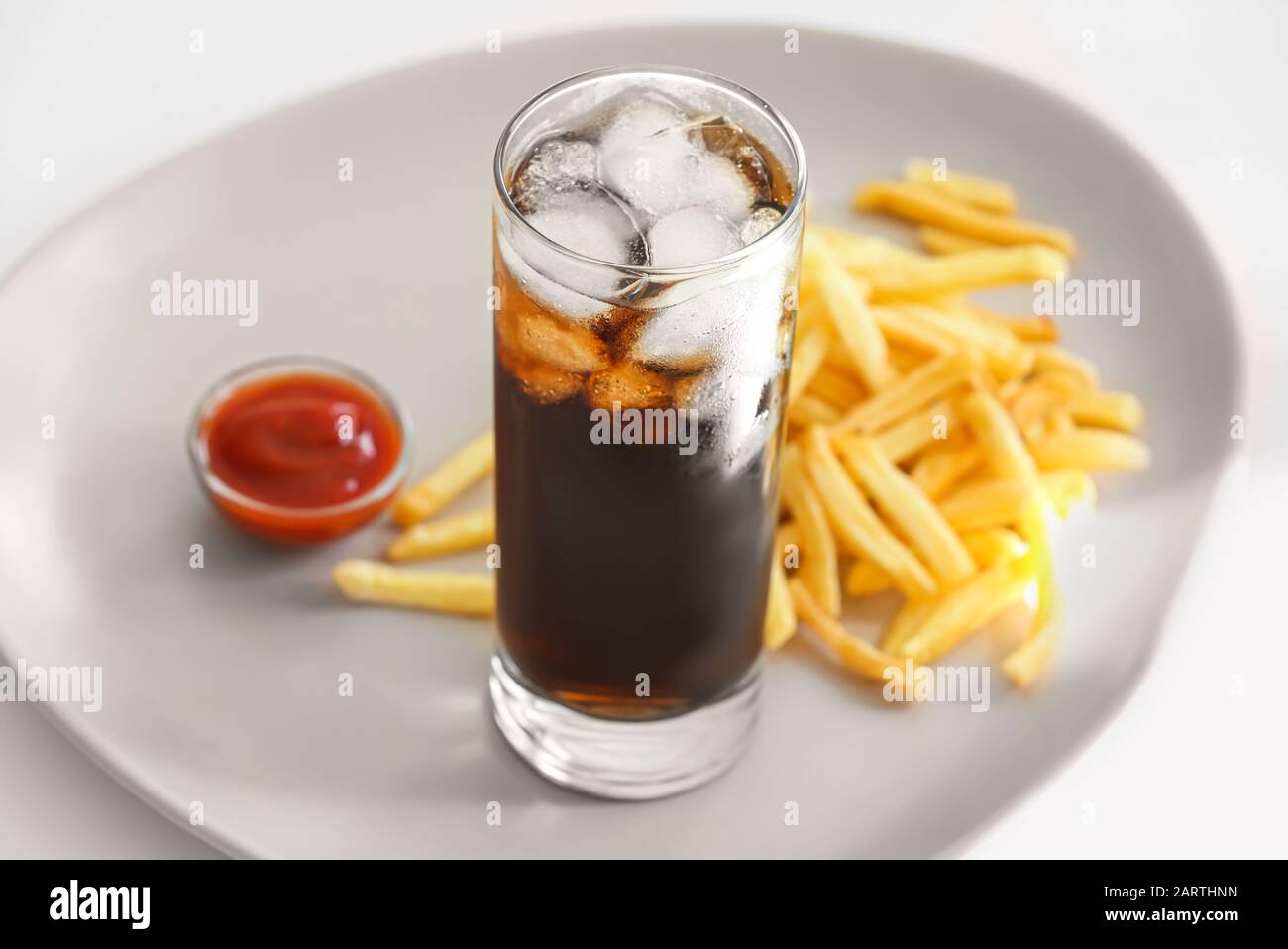 Glass of cold cola with french fries on plate Stock Photo - Alamy