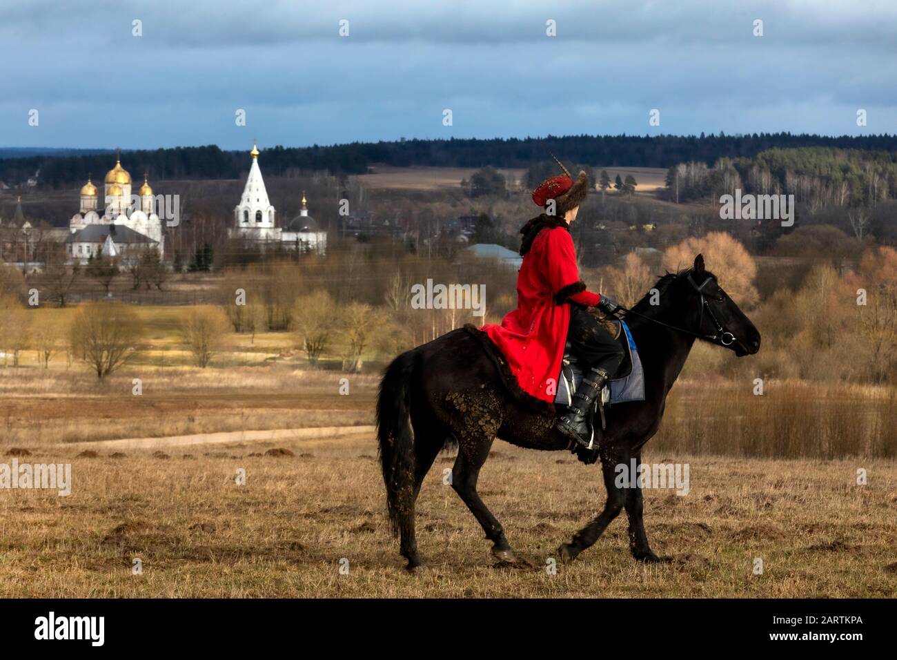 A rider in a red fur coat rides a horse against the background of an ...