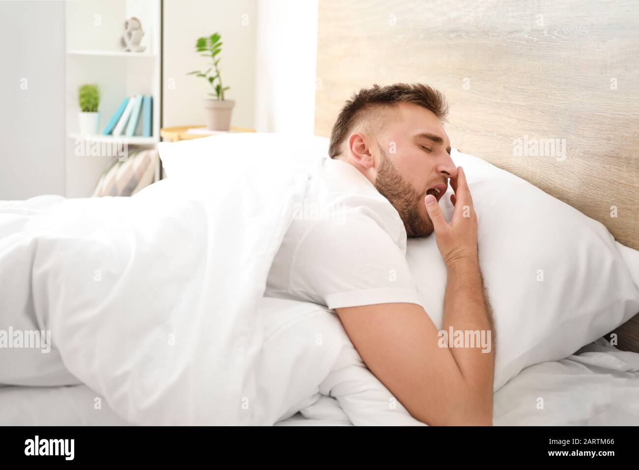 Morning of sleepy young man in bed Stock Photo - Alamy