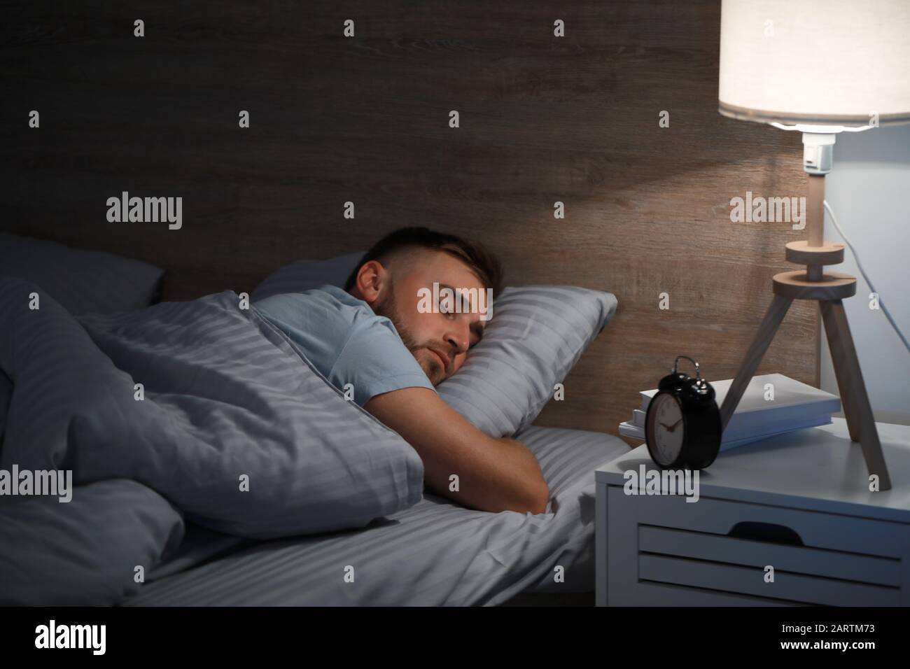 Young man sleeping in bed at night Stock Photo - Alamy