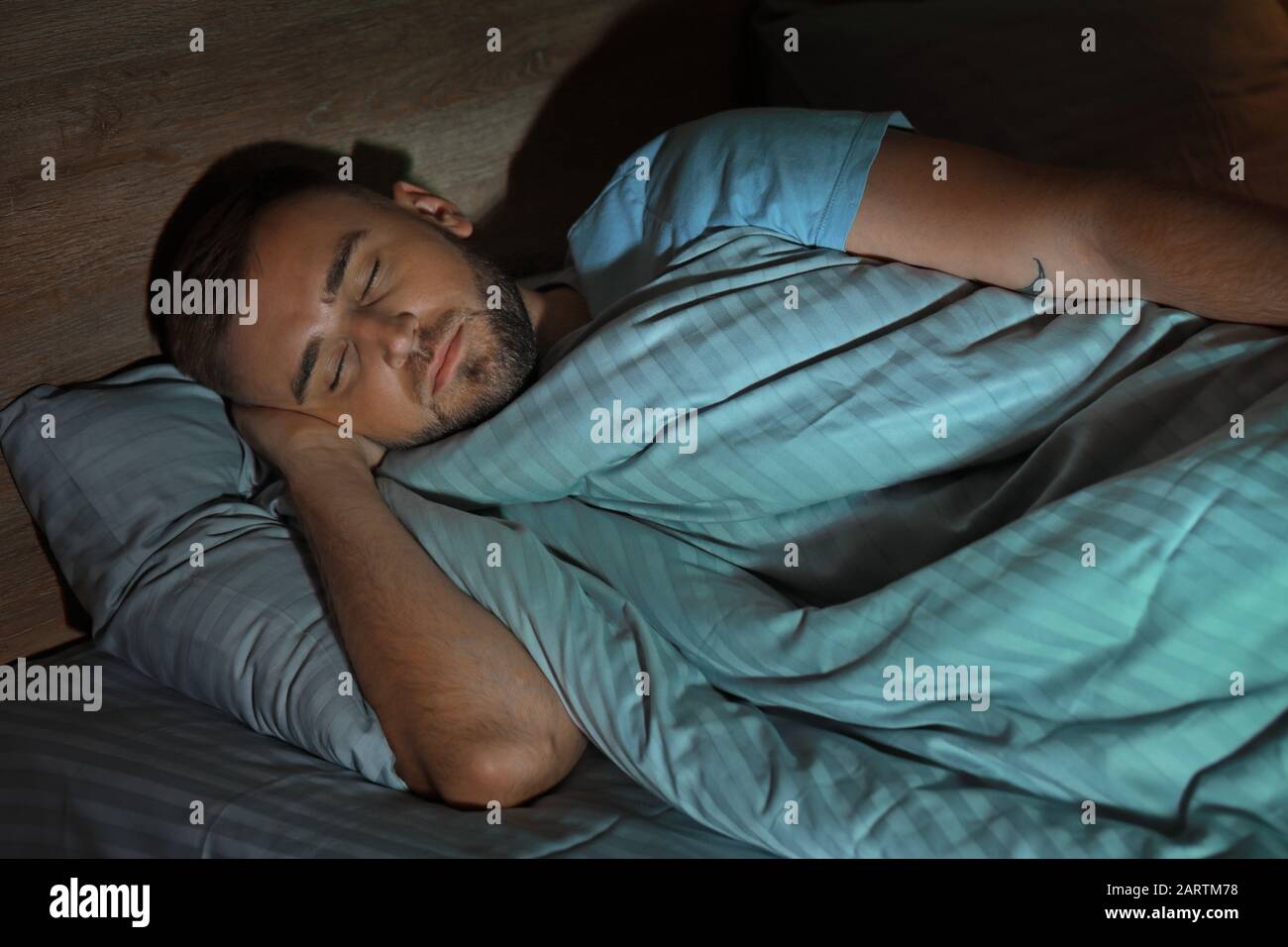 Young man sleeping in bed at night Stock Photo - Alamy