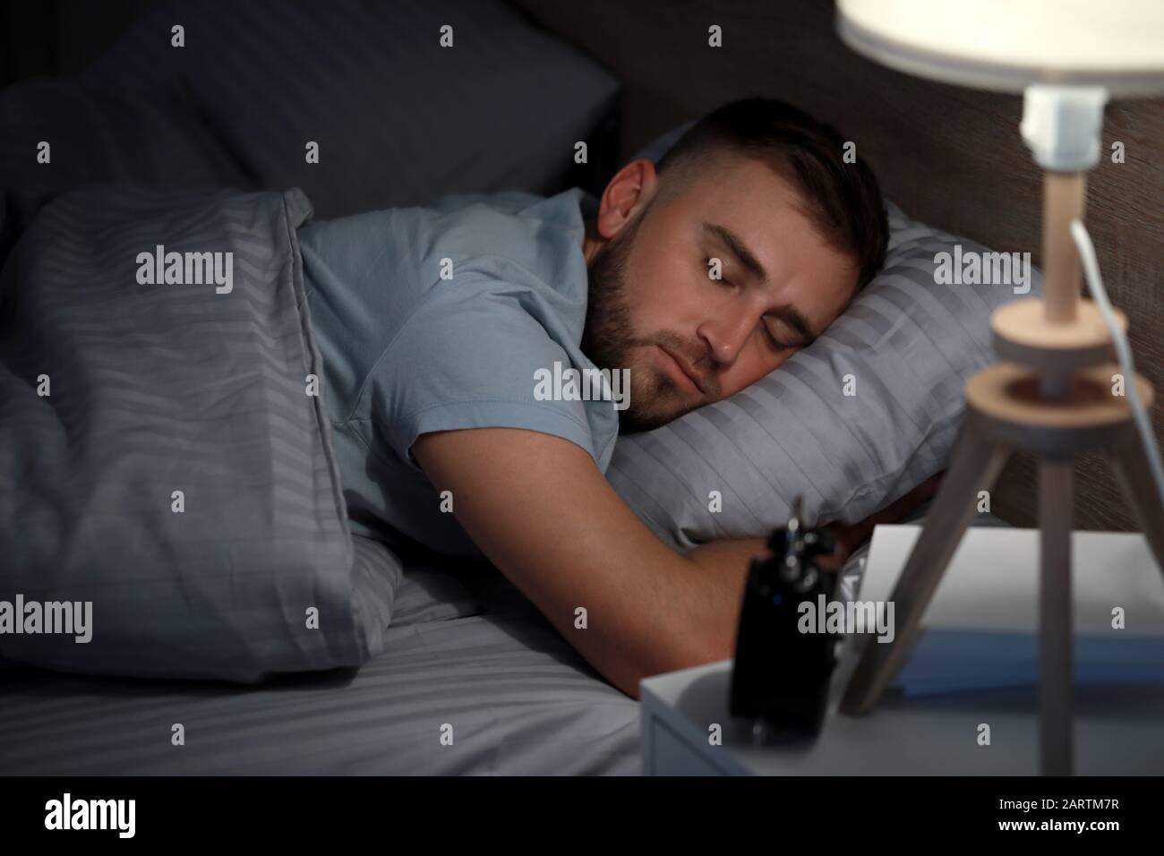 Young man sleeping in bed at night Stock Photo - Alamy