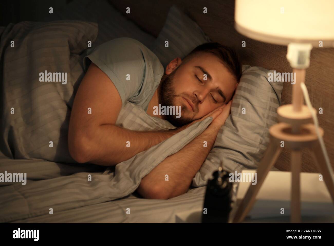 Young man sleeping in bed at night Stock Photo - Alamy