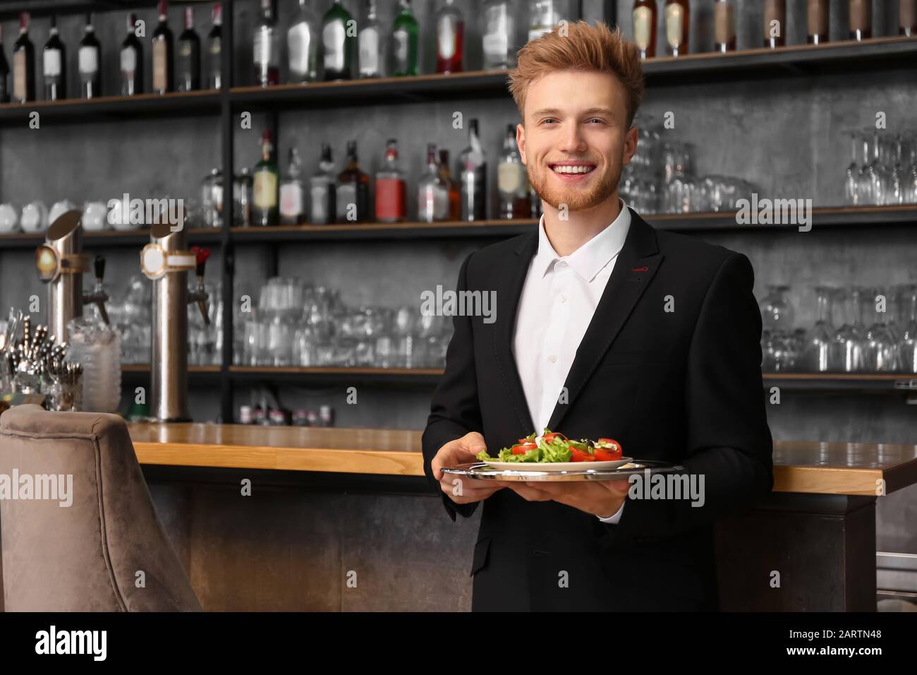Young male waiter with dish in restaurant Stock Photo - Alamy
