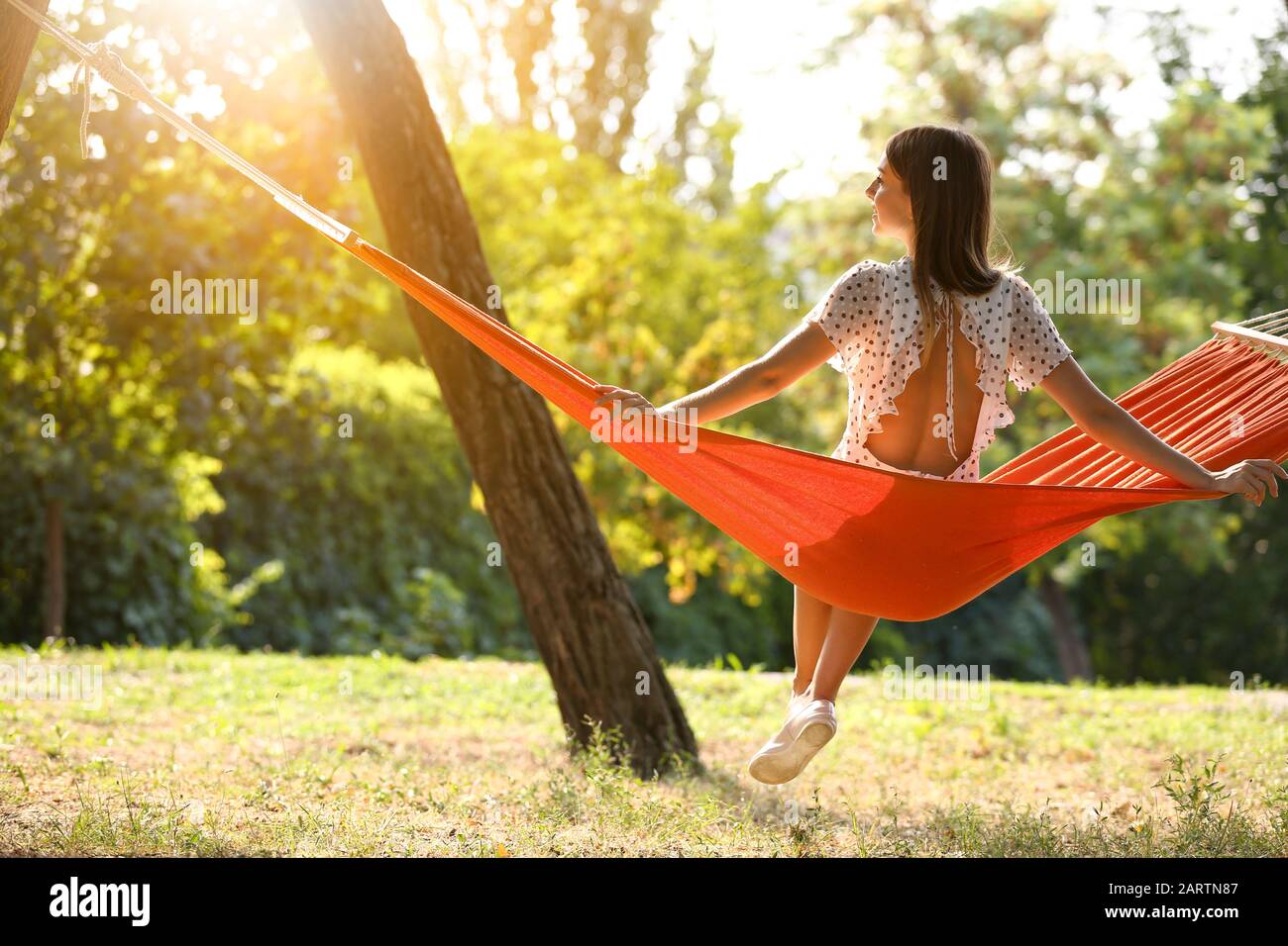 Happy young woman sitting in hammock outdoors Stock Photo - Alamy
