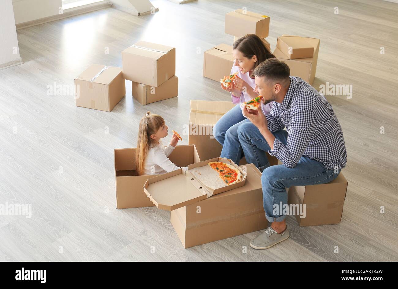 Happy family eating pizza on moving day Stock Photo - Alamy