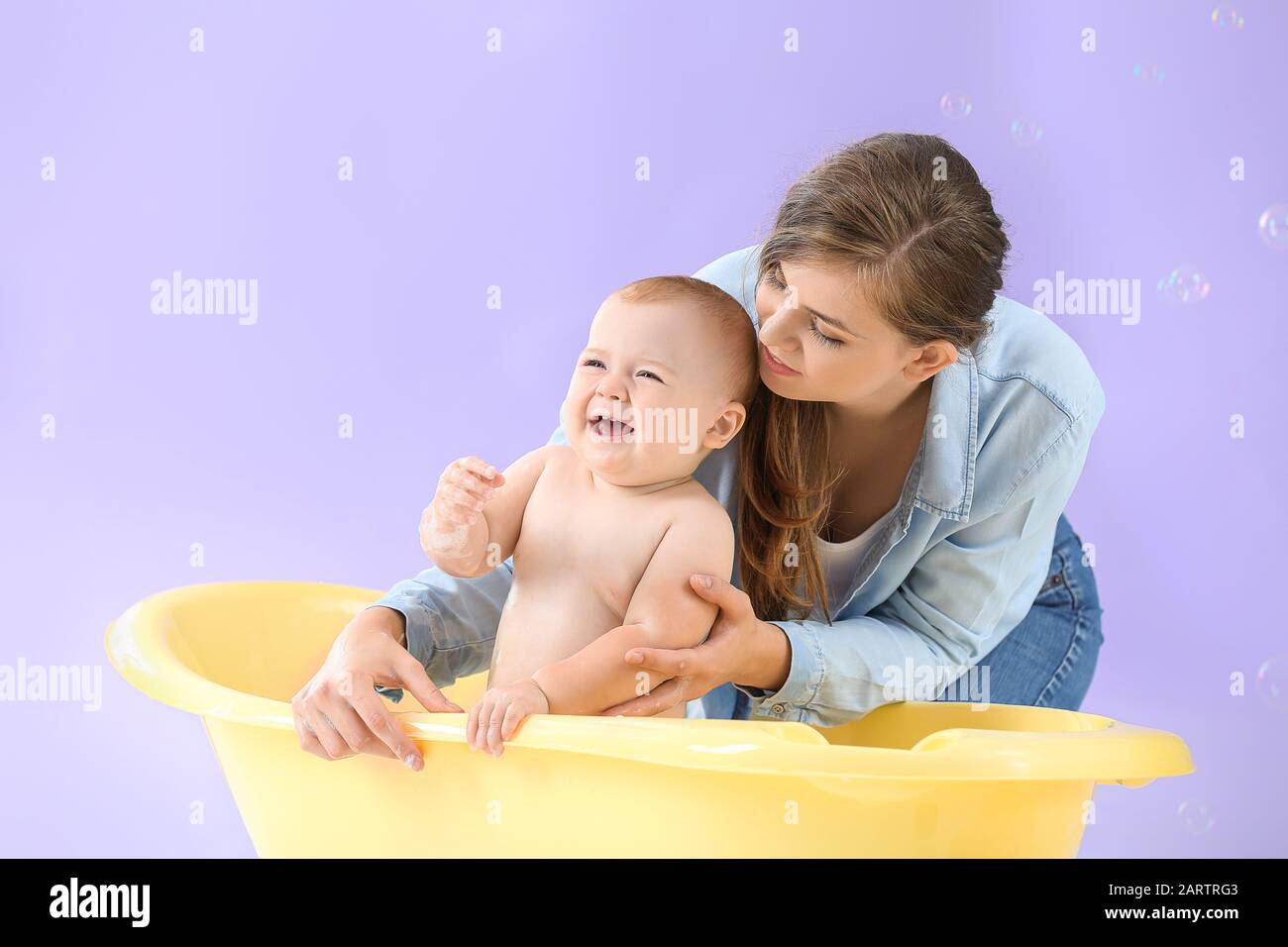 Mother bathing her cute baby on color background Stock Photo - Alamy