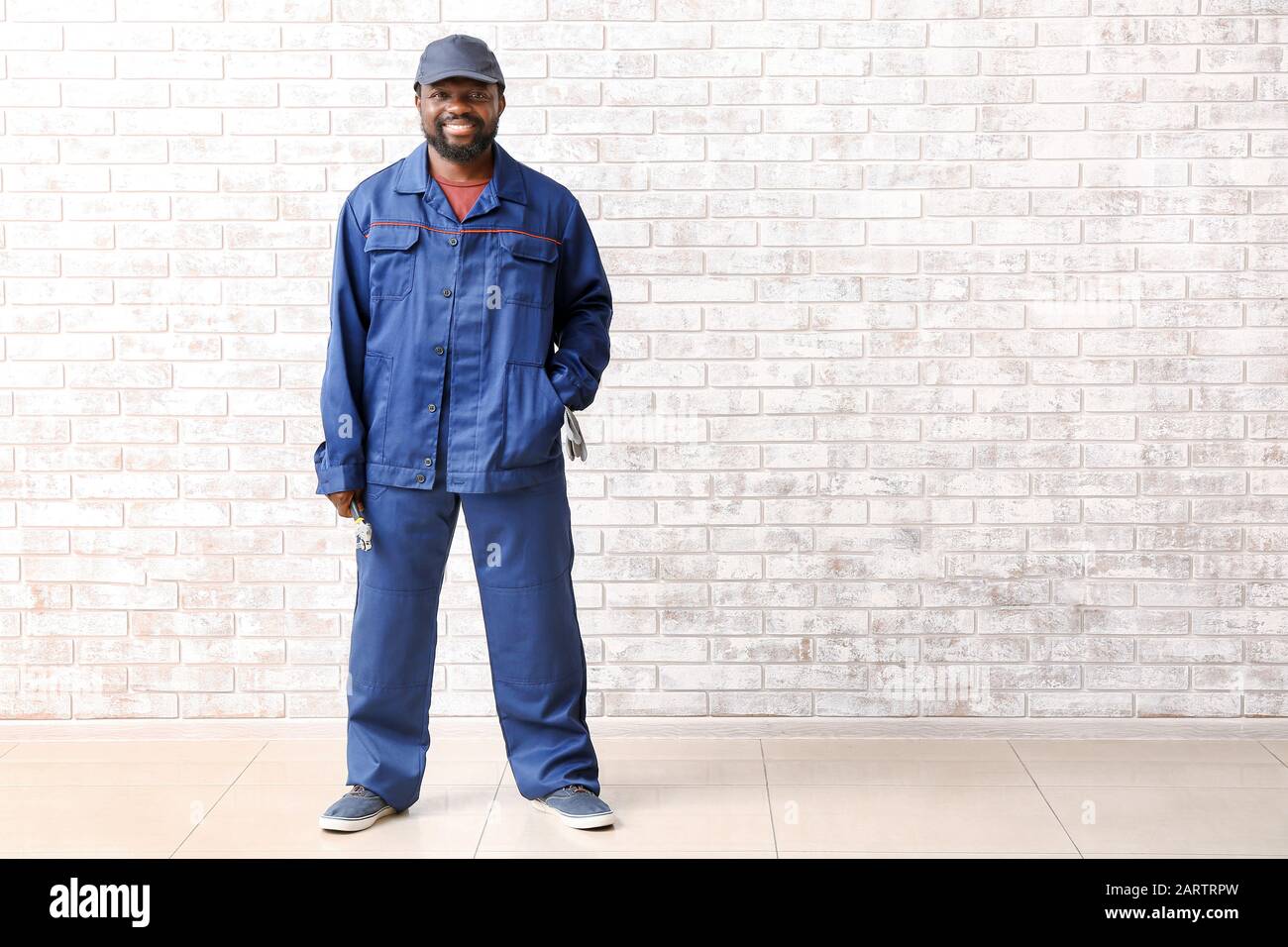 African-American car mechanic near brick wall Stock Photo - Alamy