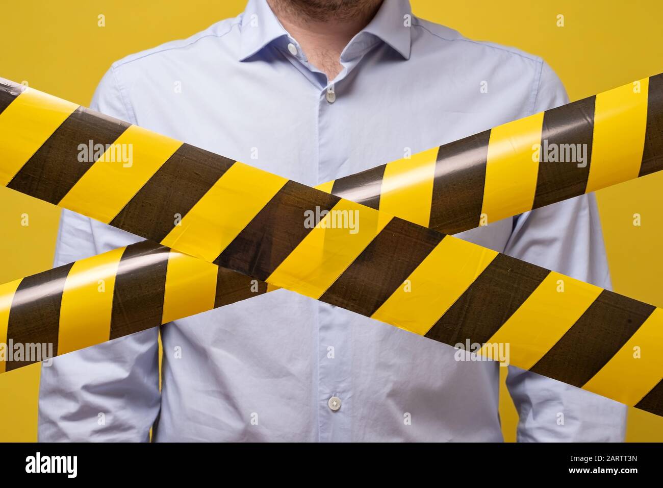 Man standing behind black and yellow lines of barrier tape that forbids ...
