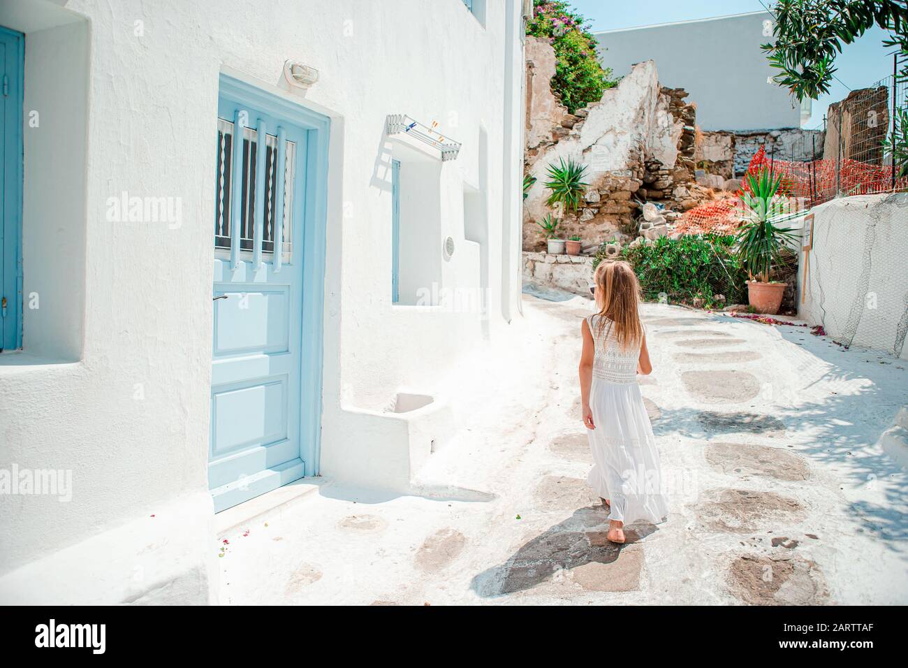 Adorable little girl at old street of typical greek traditional village ...
