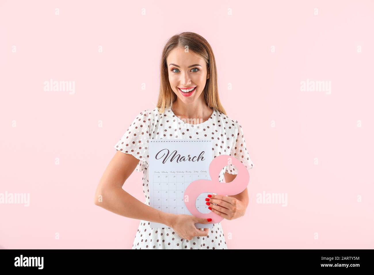 Beautiful young woman with figure 8 and calendar on color background ...