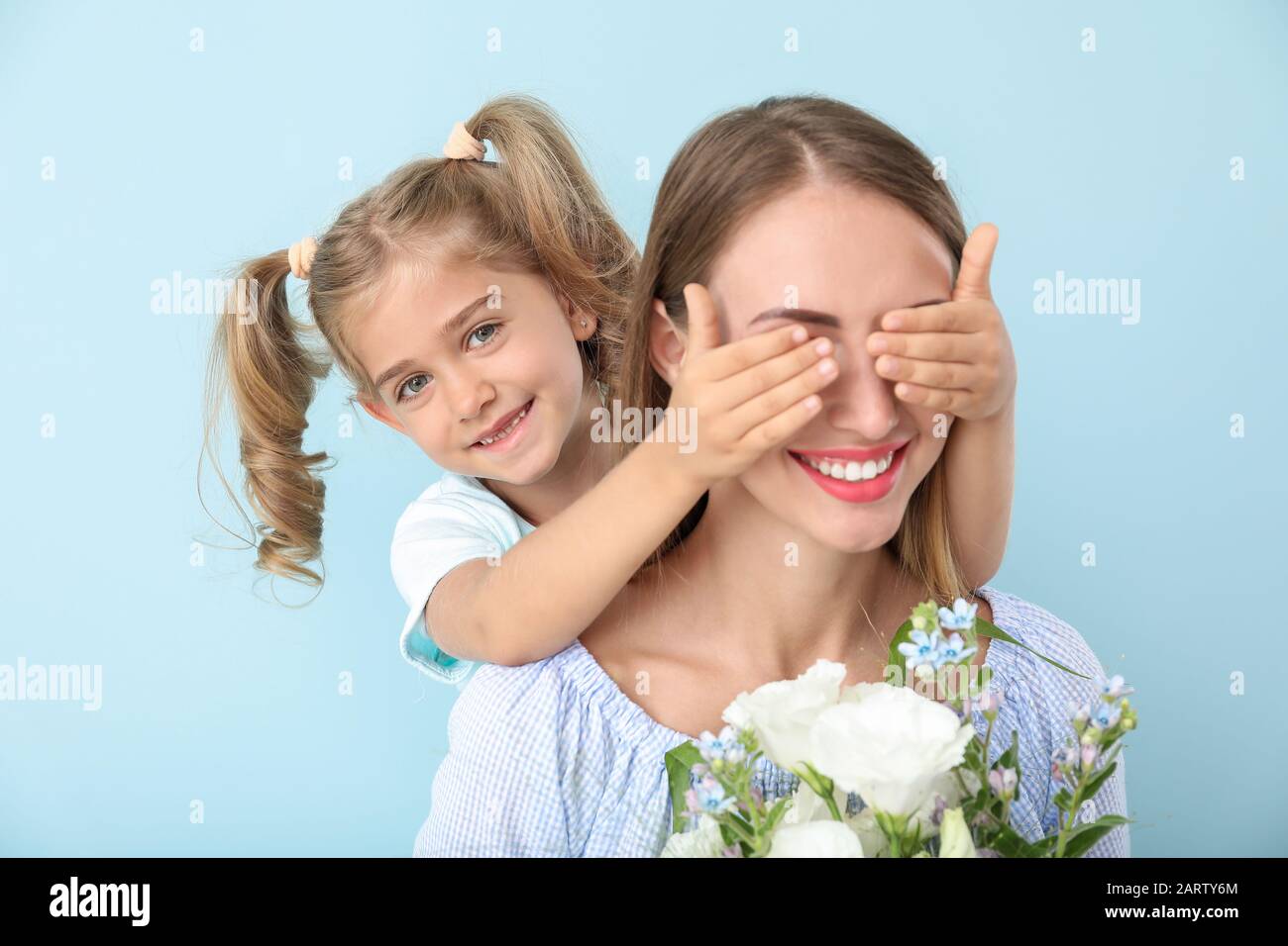 Little girl greeting her mother on color background Stock Photo - Alamy
