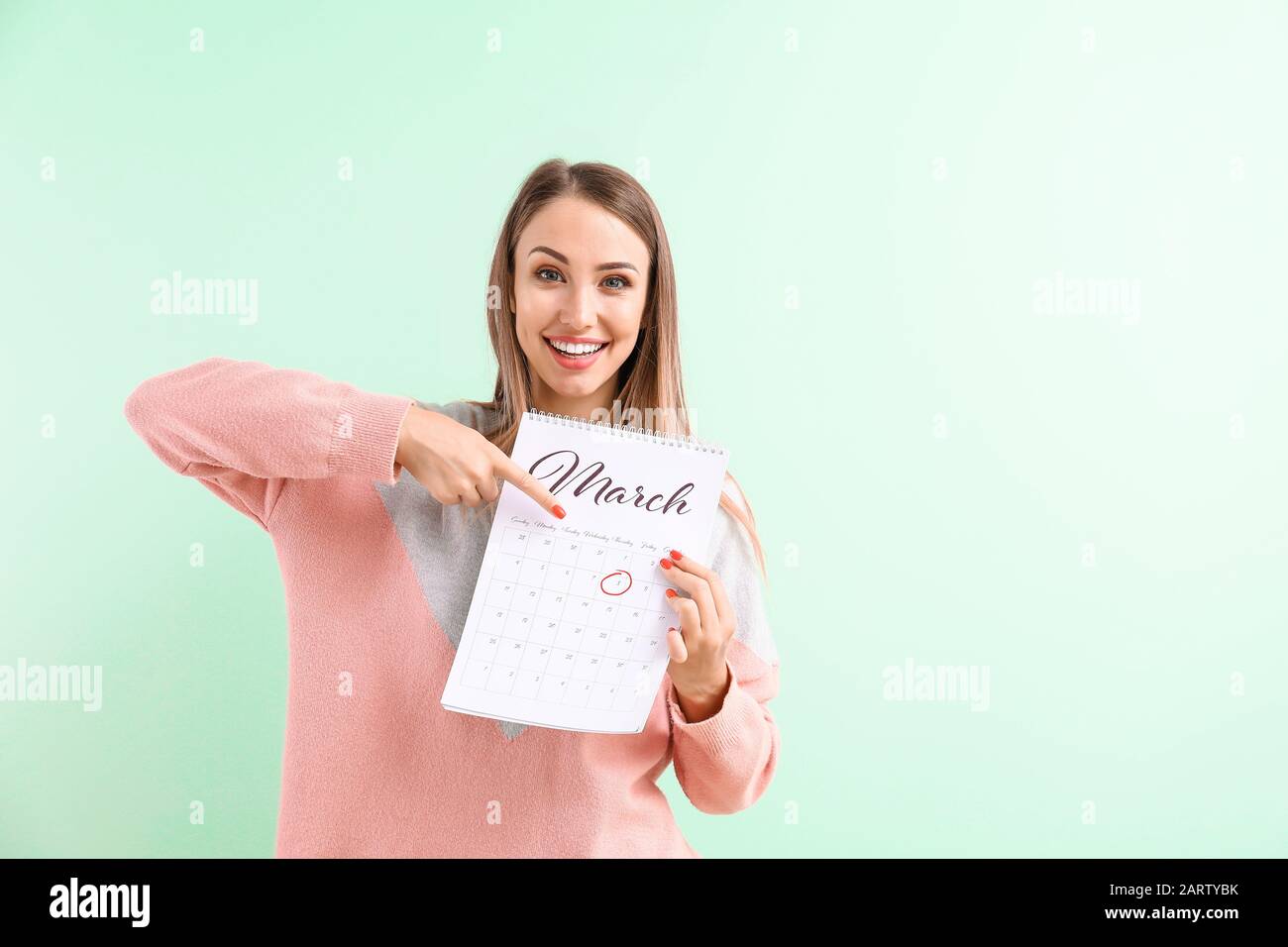 Beautiful young woman with calendar on light background. International ...