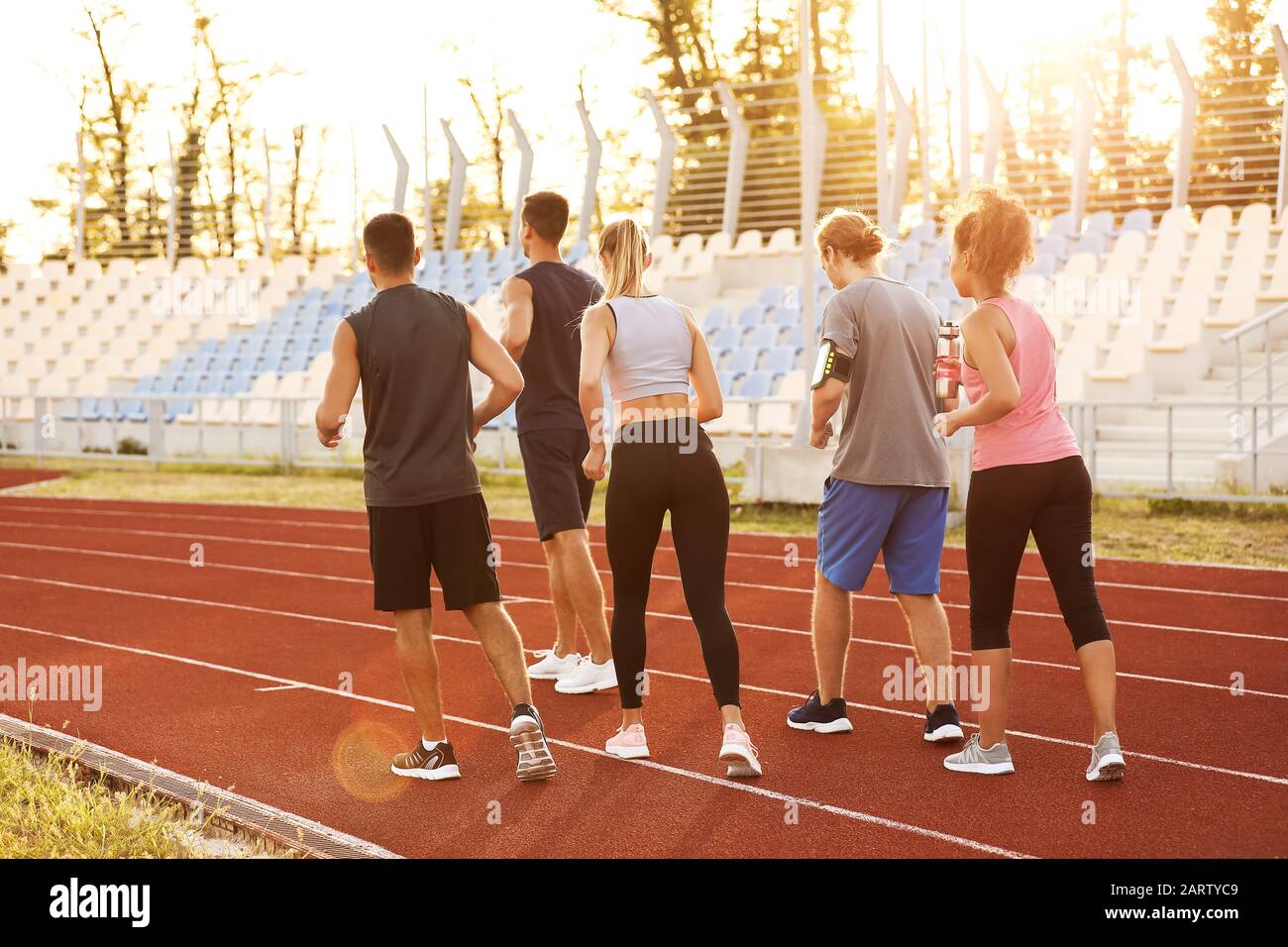 Sporty young people running at the stadium Stock Photo - Alamy