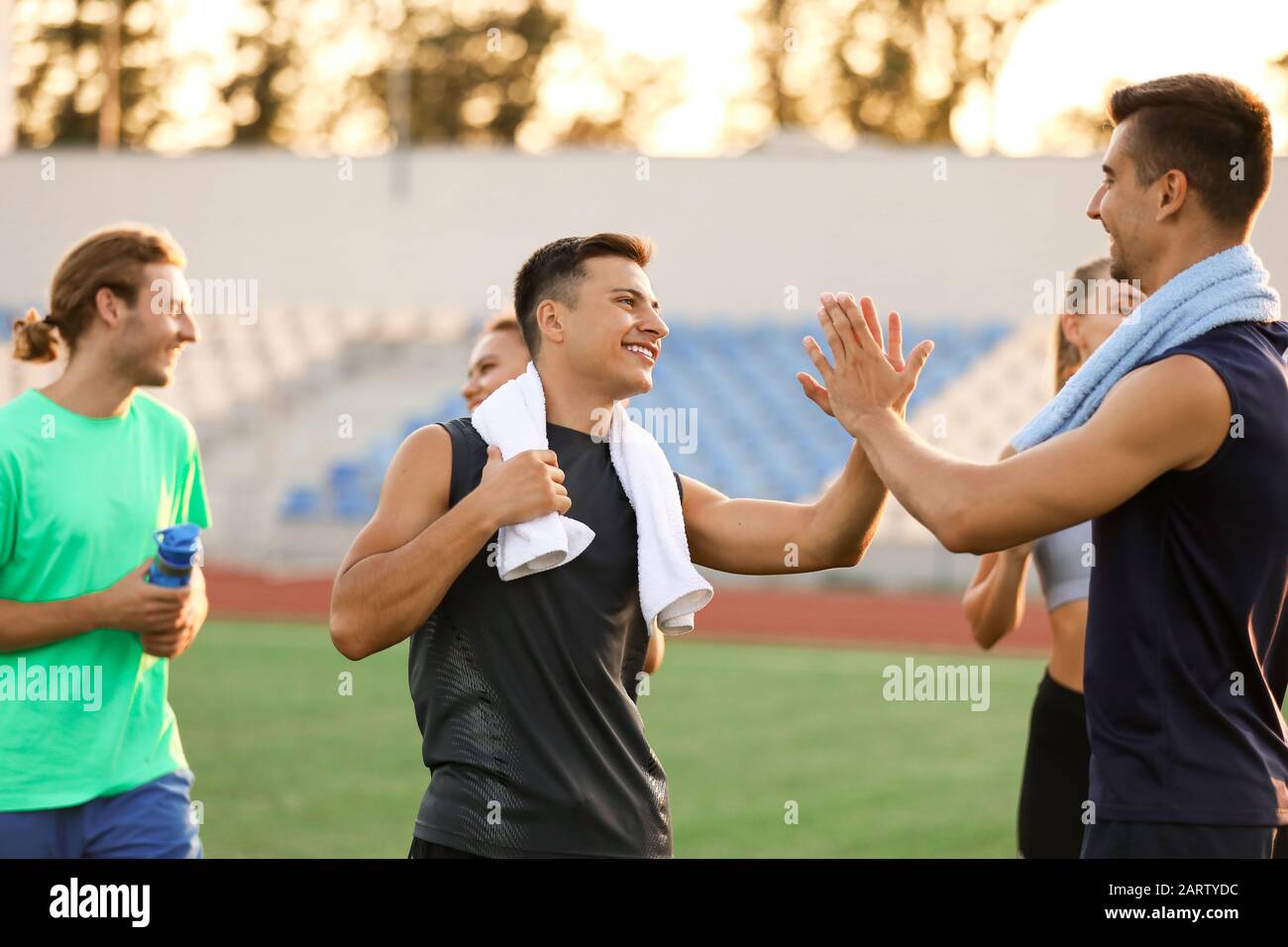 Sporty young men giving each other high-five at the stadium Stock Photo ...