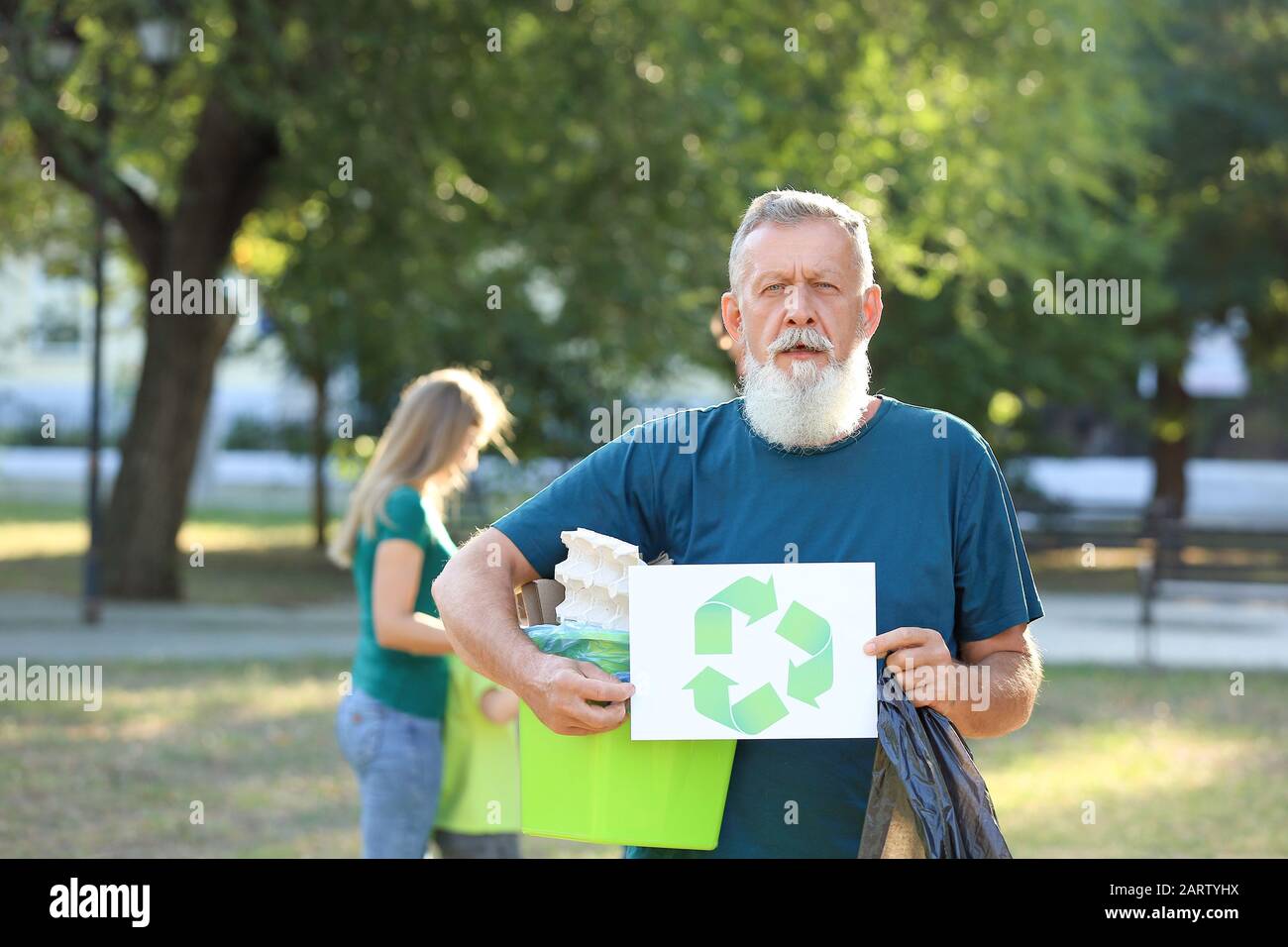 Man holding gathered garbage and paper sheet with symbol of recycling ...