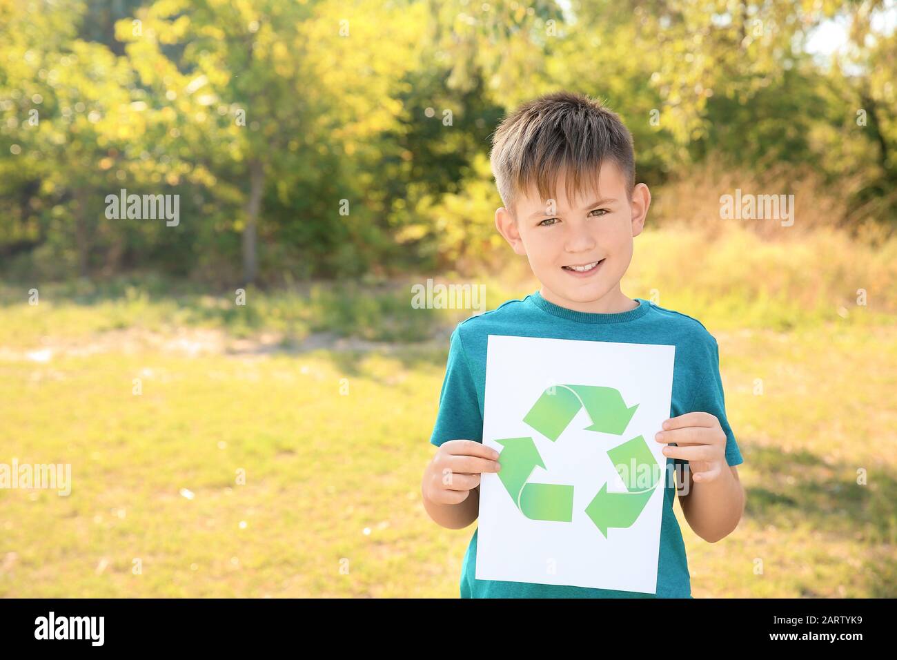 Boy holding paper sheet with sign of recycling outdoors Stock Photo - Alamy