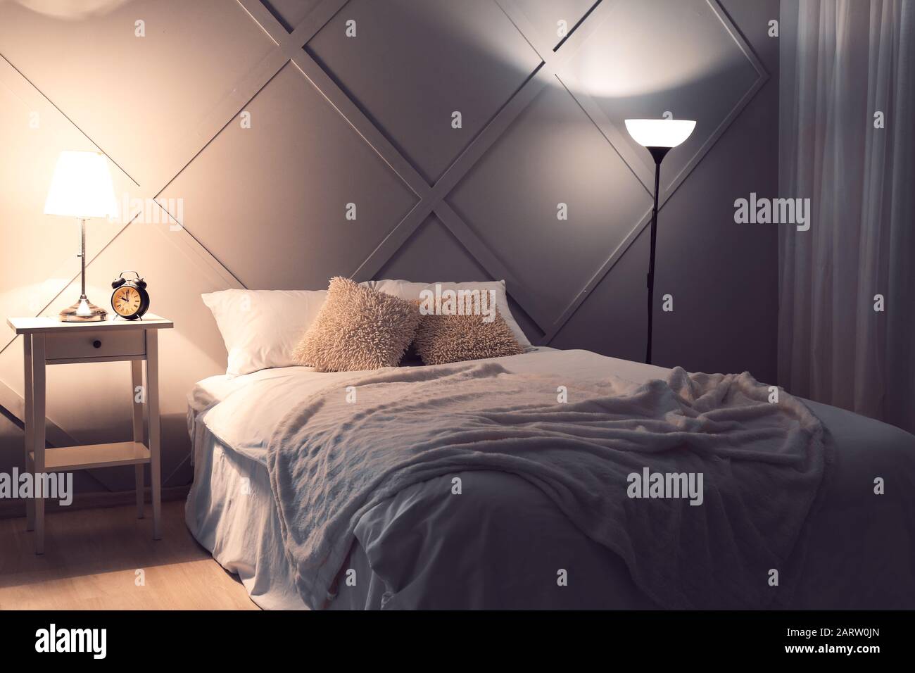 Big comfortable bed in interior of room at night Stock Photo - Alamy