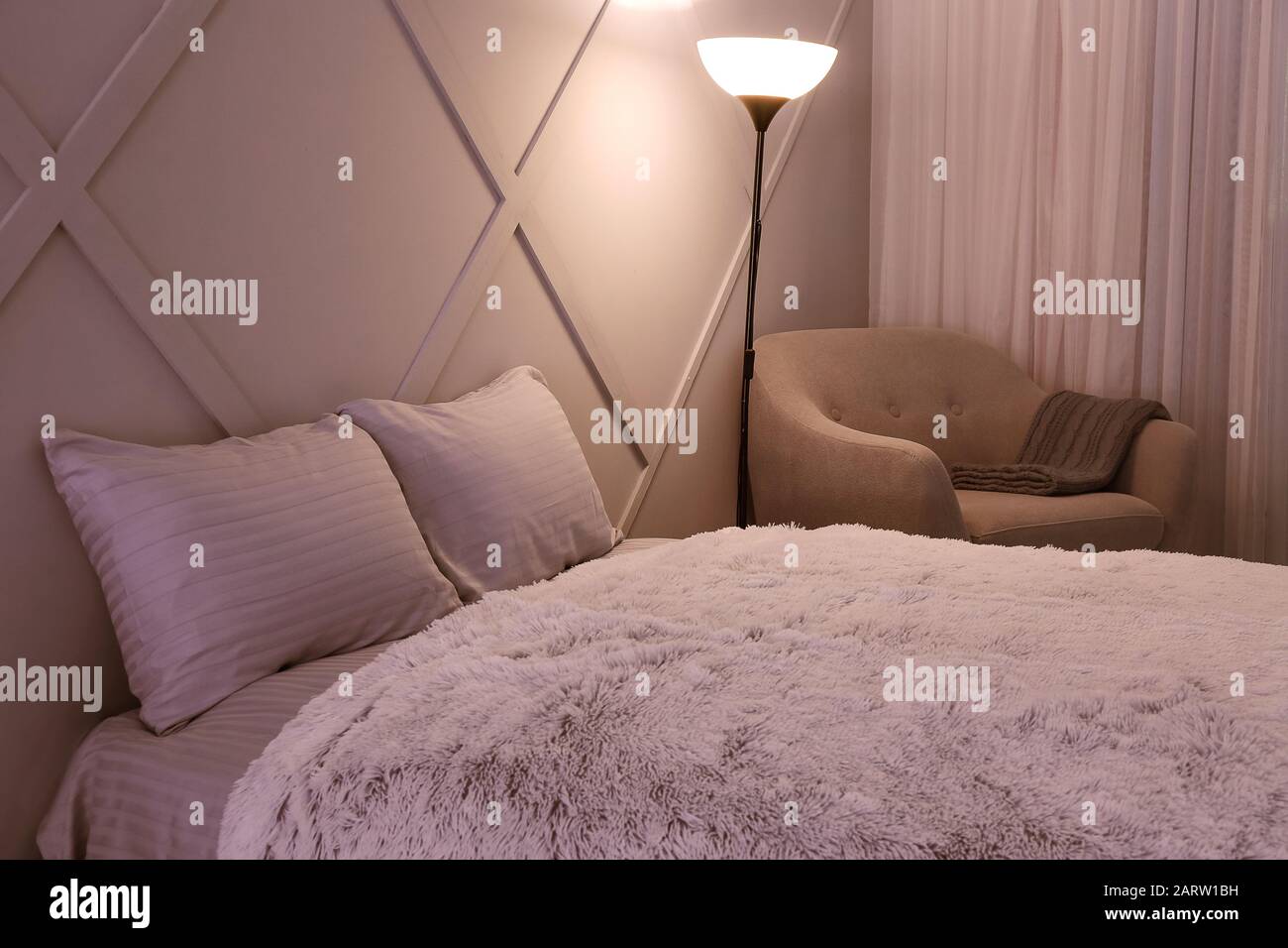Big comfortable bed in room at night Stock Photo - Alamy