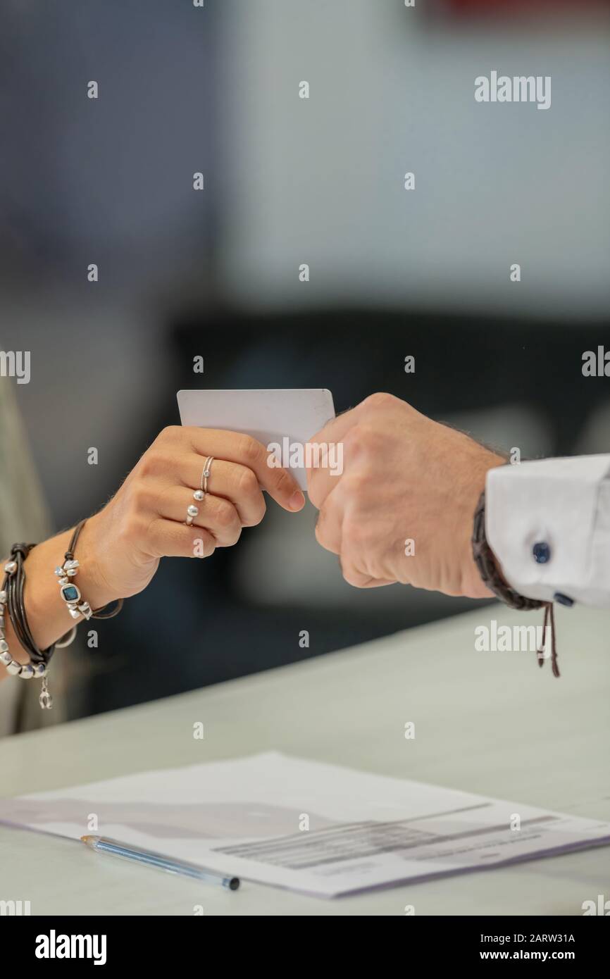 Close-up of a female hand giving a credit card to a male hand over a ...