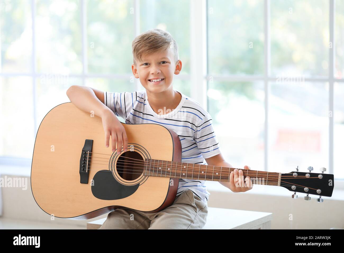Little boy playing guitar near window Stock Photo - Alamy
